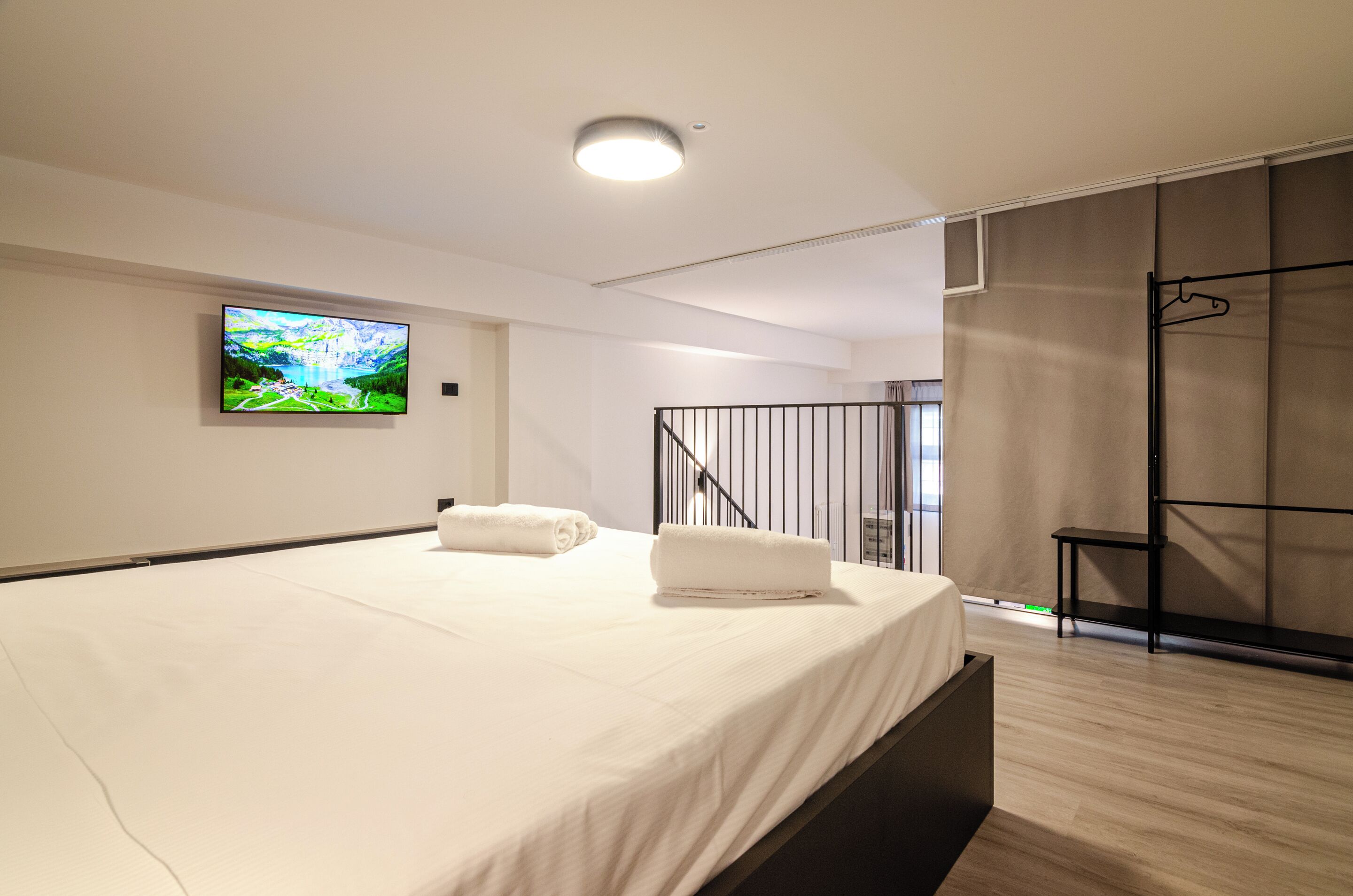 Quarto de hotel moderno com uma cama grande, televisão de tela plana na parede e varanda com vista.
