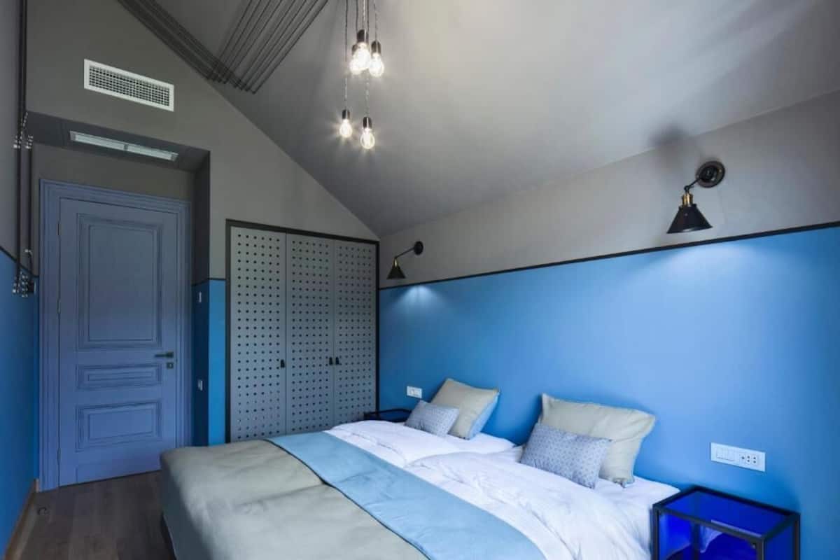 Quarto com cama, guarda-roupa, escrivaninha e parede azul.