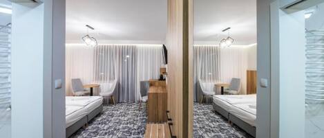 Quarto de hotel com duas camas, um banco de madeira, uma TV e um espelho.