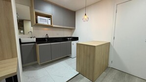 Cozinha moderna com armários cinza, bancada preta e ilha de madeira.