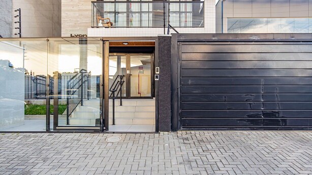 Um edifício moderno com entrada de vidro, escada visível e porta de garagem preta.
