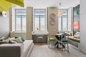 Um quarto moderno e bem iluminado, com uma janela grande, área de refeições e um espaço de estar aconchegante.