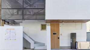 Um edifício moderno com fachada de vidro extensa, porta de madeira e pequena janela.
