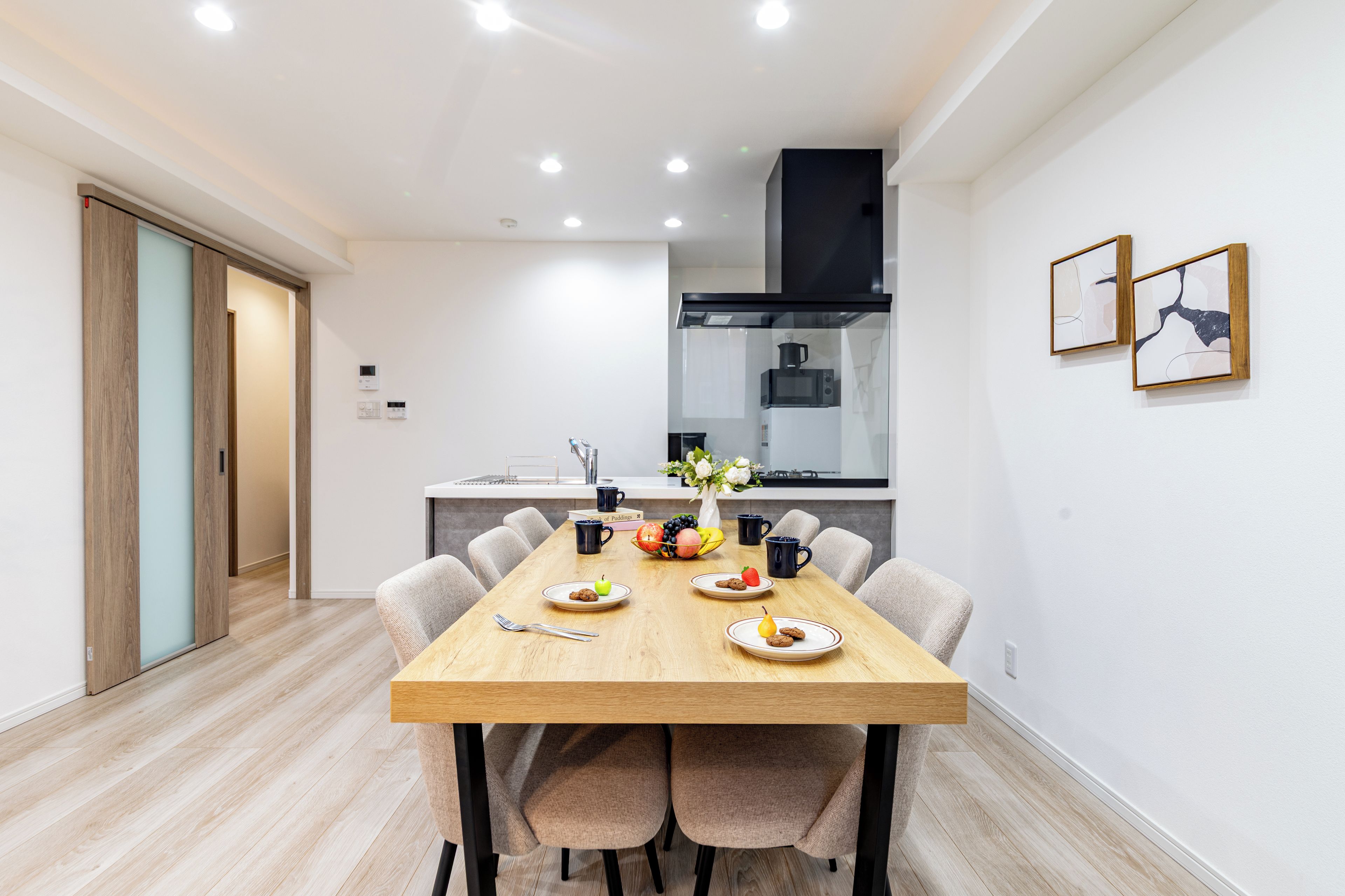 Cozinha moderna com mesa de jantar posta para dois, equipada com eletrodomésticos básicos e um vaso de flores.
