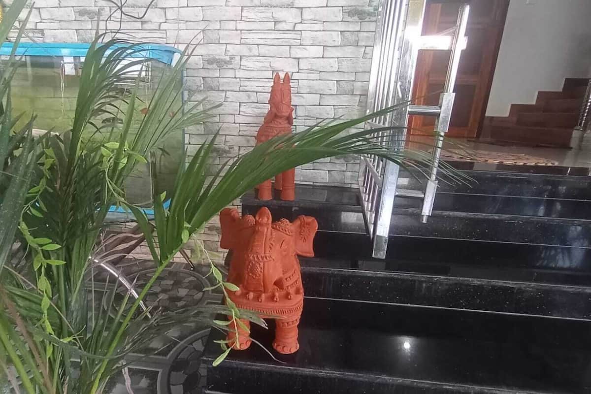 Uma escadaria com uma estátua vermelha, guarda-corpo de vidro e uma planta.