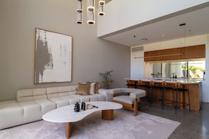 Uma sala de estar moderna com um sofá, mesa de centro e uma grande pintura abstrata.