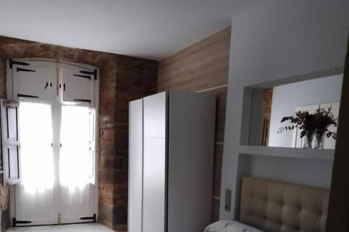 Quarto com cama, guarda-roupa e porta de acesso a outro cômodo.