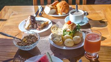Uma mesa com diversos alimentos, um copo de suco e uma tigela de cereal.