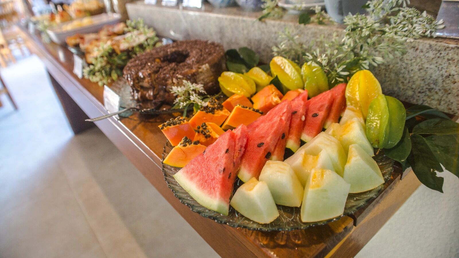 Buffet com diversas frutas e sobremesa de chocolate.