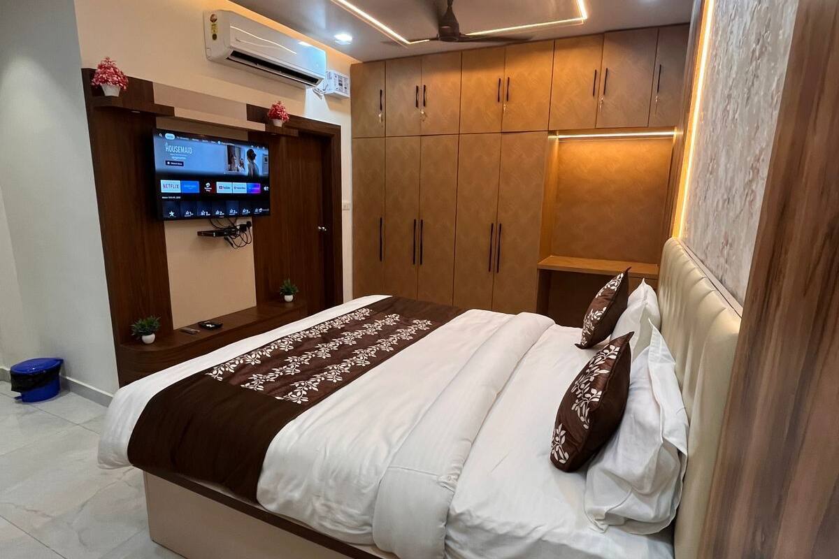 Quarto moderno com cama, televisão na parede, guarda-roupa e telefone de mesa.