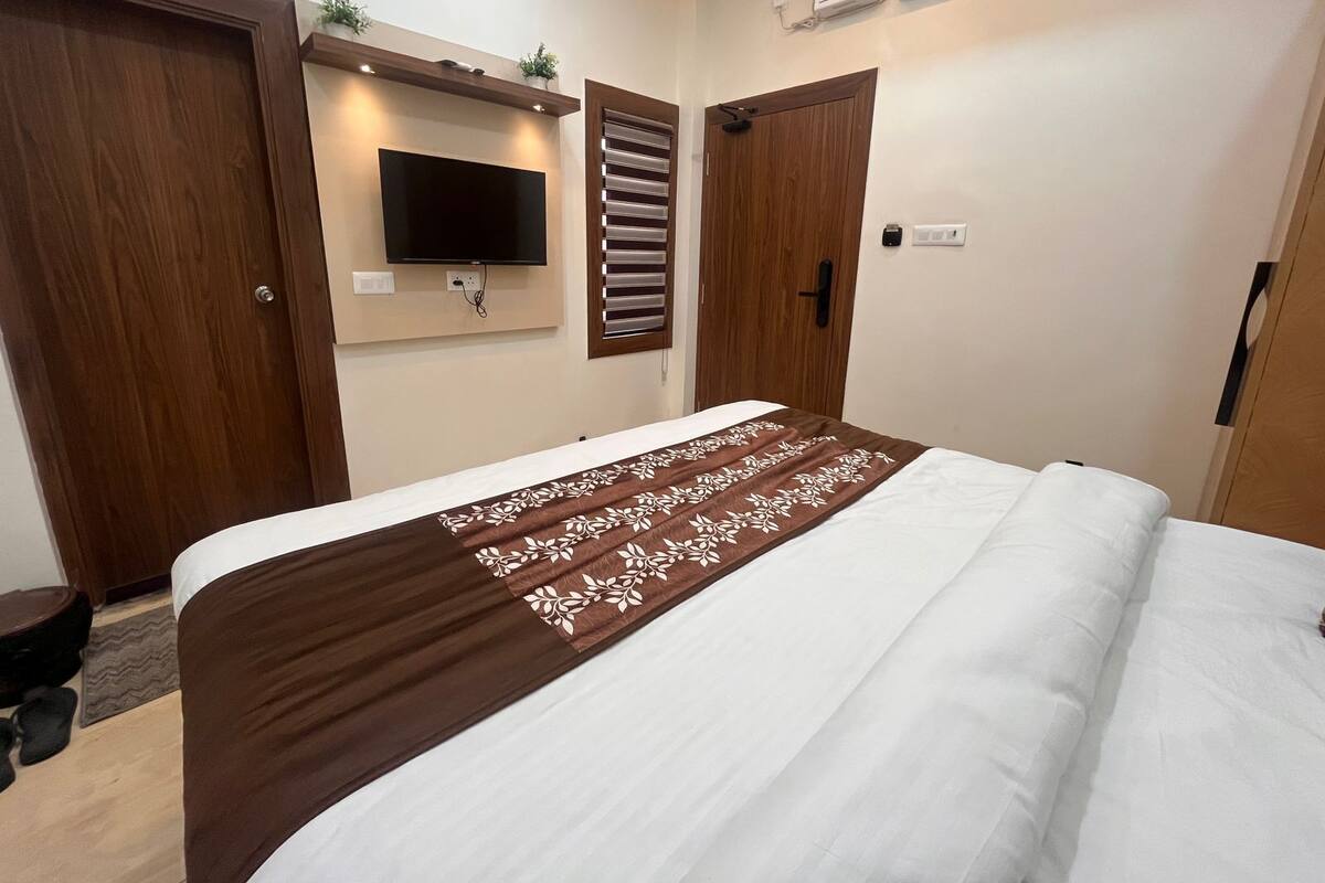 Quarto com cama, televisão na parede, porta e ar-condicionado.