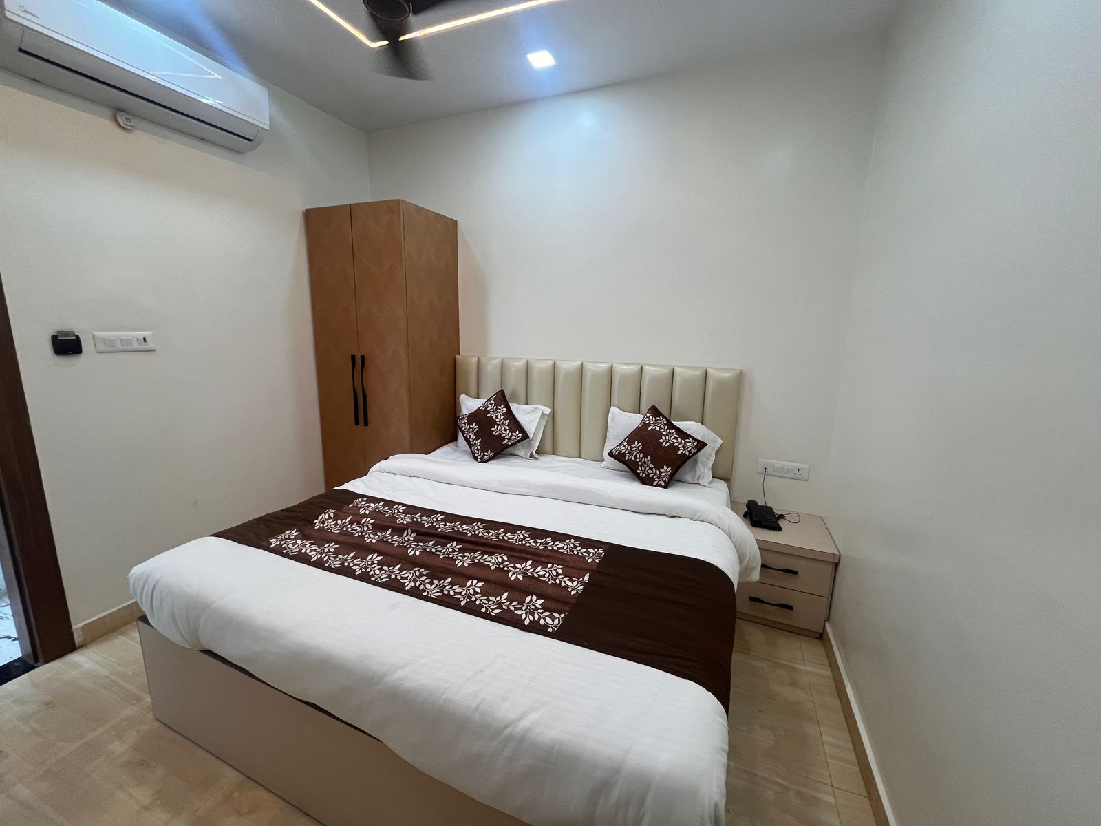 Quarto com cama, guarda-roupa, mesa de cabeceira e ventoinha no teto.