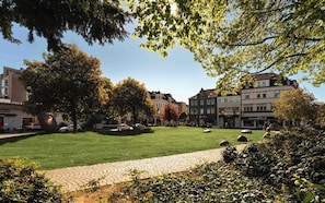 Um pátio com calçada pavimentada, gramado verde e edifícios ao redor.
