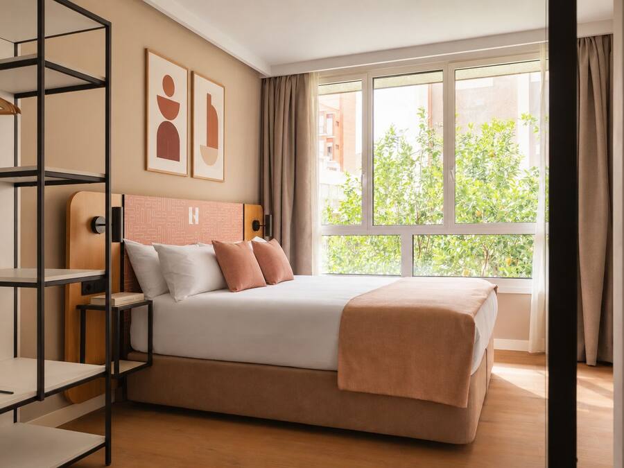 Quarto moderno com uma cama grande, cabeceira de madeira, roupeiro embutido e vista para o verde lá fora.