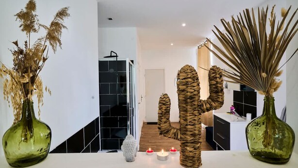 Cozinha moderna com bancada branca, escultura de cacto e um vaso verde com plantas secas.