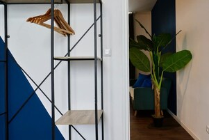 Um quarto com uma estante de metal, uma planta em vaso e uma parede azul.