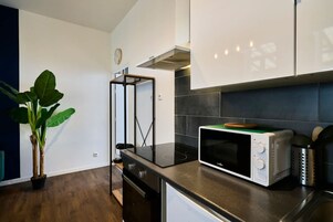 Uma cozinha moderna com micro-ondas, fogão e um vaso de planta.
