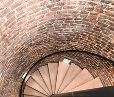 Uma escadaria em espiral com um fundo de parede de tijolos.