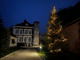 Um edifício grande e histórico, com uma torre imponente e um caminho bem iluminado que leva à entrada.