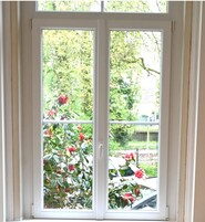 Janela com moldura branca e vista para um jardim e um carro do lado de fora.