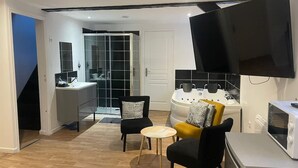 Uma sala de estar moderna com televisão de tela plana, um sofá, uma mesa redonda pequena e um micro-ondas.
