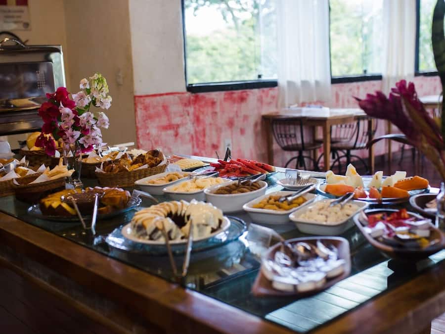 Buffet com diversos pratos, micro-ondas e janela com vista para o verde.