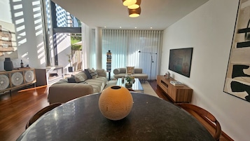 Uma sala de estar moderna com uma mesa redonda, sofás, uma mesa de centro e uma televisão.
