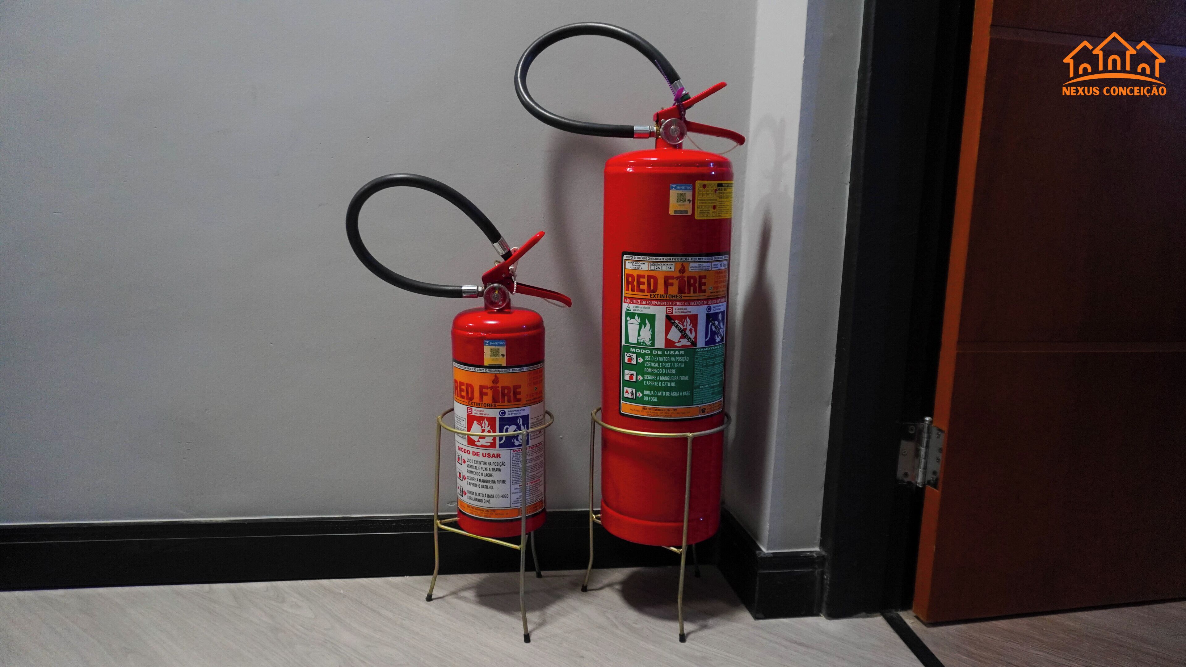 Dois extintores de incêndio fixados verticalmente numa parede perto de uma porta.