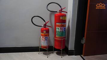 Dois extintores de incêndio fixados verticalmente numa parede perto de uma porta.