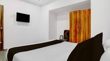 Quarto de hotel com uma cama, televisão fixada na parede e um guarda-roupa de madeira.