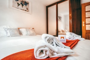 Quarto de hotel com uma cama, um guarda-roupa de madeira e um cobertor vermelho.