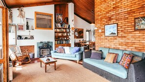 Uma sala de estar acolhedora com lareira, estantes de livros e um sofá azul.