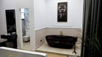 Um banheiro moderno com uma banheira independente, um espelho e uma obra de arte emoldurada na parede.