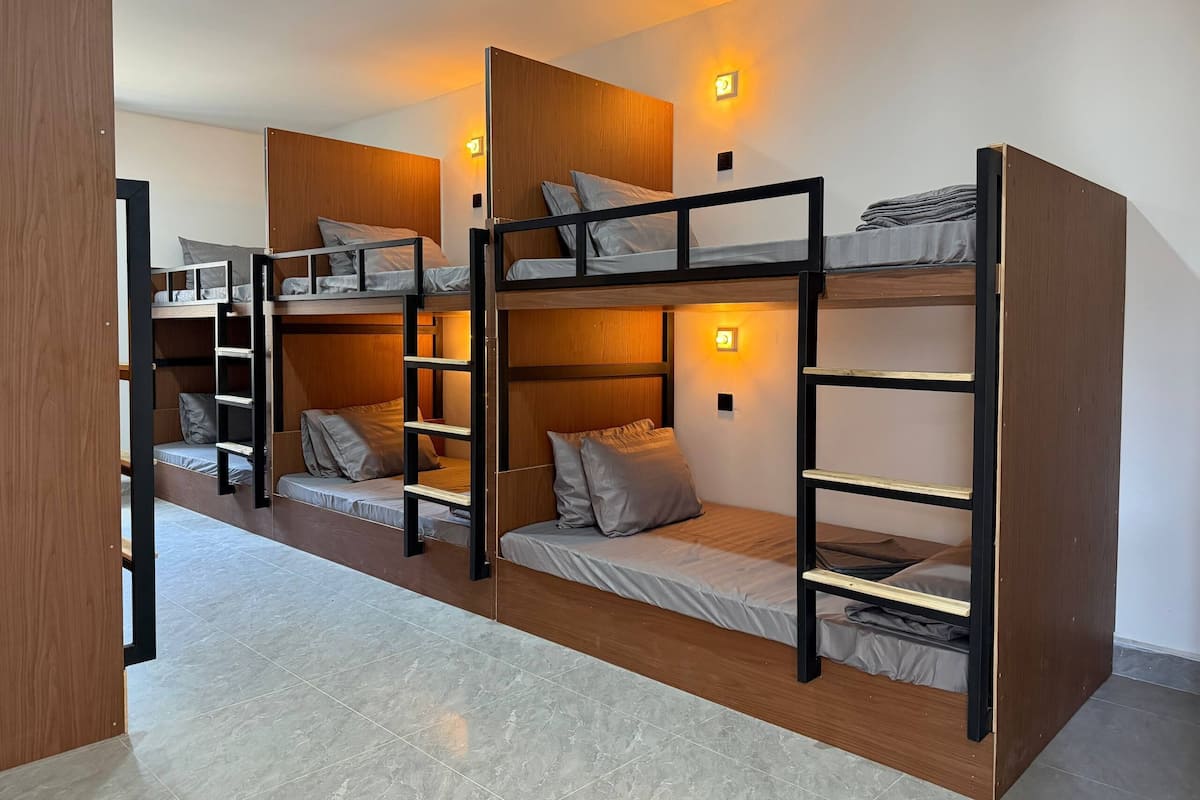 Quarto com beliches de madeira, prateleiras embutidas e luzes fixadas na parede.