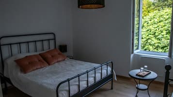 Um quarto com uma cama, uma mesa de cabeceira, uma janela e um lustre.