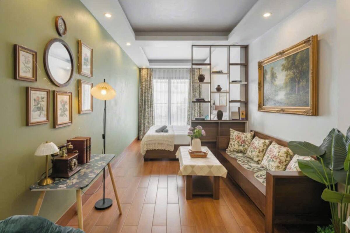 Uma sala de estar com sofá, mesa, abajur e um quadro na parede.