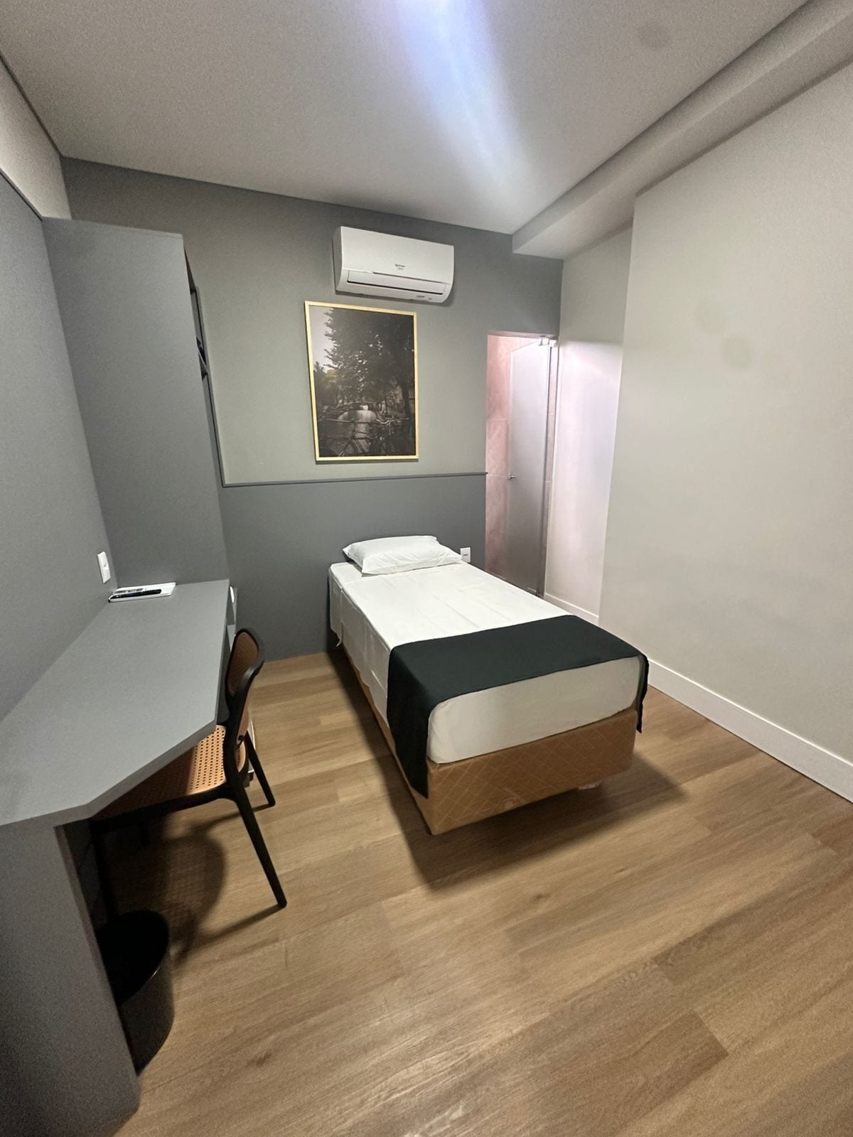 Um quarto com cama, escrivaninha e cadeira.
