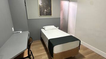 Um quarto com cama, escrivaninha e cadeira.