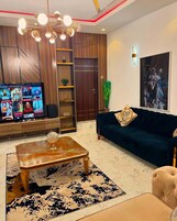 Sala de estar com televisão, sofá, mesa de centro e objetos decorativos.