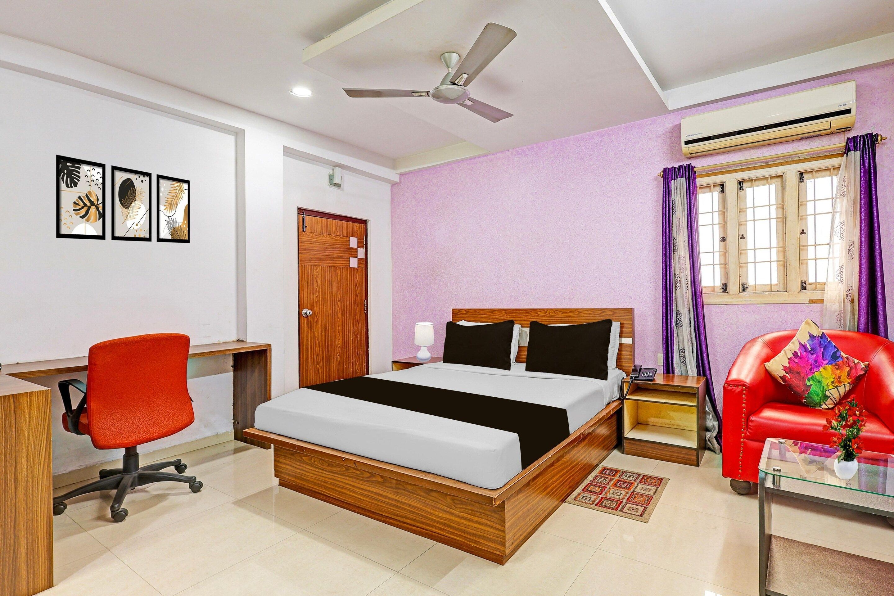 Quarto com cama, escrivaninha, cadeira e um sofá vermelho.