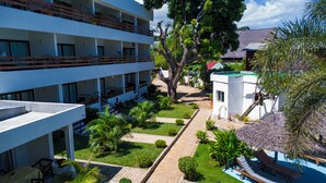 Um hotel com vários andares, área externa para sentar e um jardim bem cuidado.