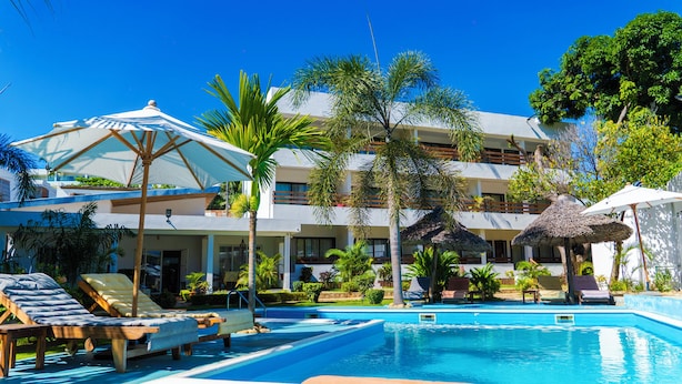Um resort com piscina, espreguiçadeiras e guarda-sóis de palha.