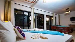 Quarto de hotel com uma cama, uma mesa e vista através de amplas janelas.