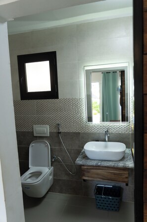 Casa de banho com sanita, lavatório e chuveiro.
