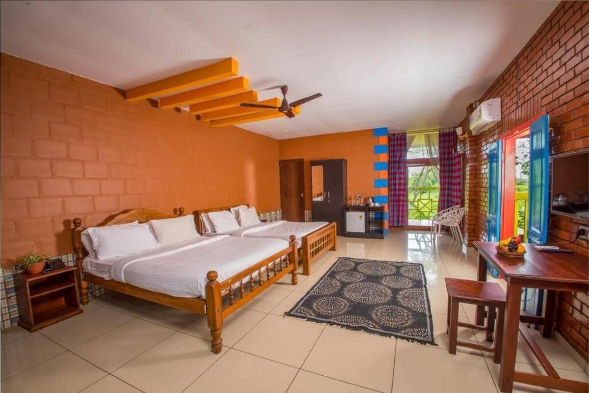 Quarto com cama, escrivaninha, cadeira, ventoinha no teto e janela.