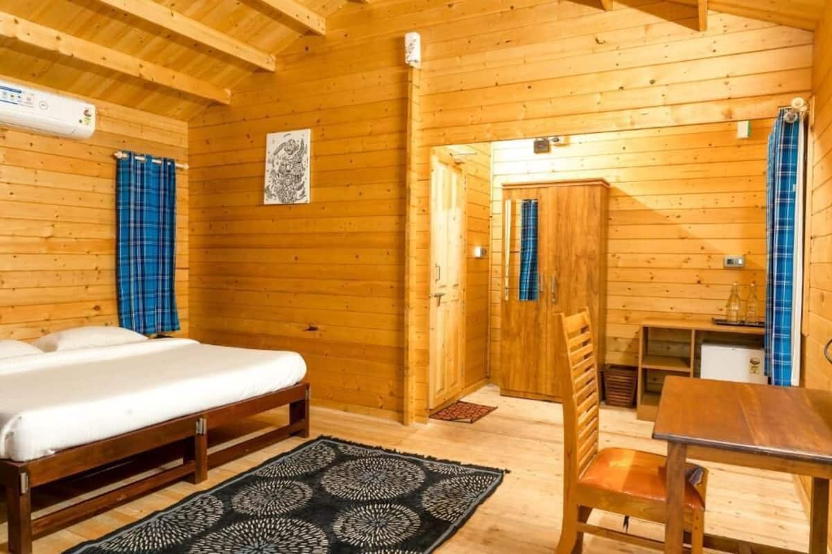 Uma cabana de madeira com uma cama, uma mesa e uma cadeira.