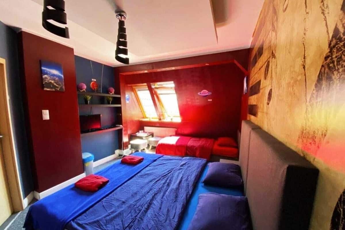 Um quarto com uma cama, uma escrivaninha e uma janela.