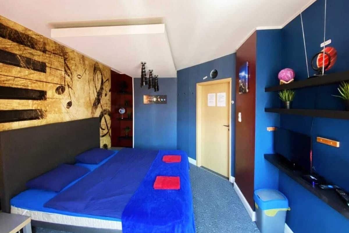 Quarto com cama, porta, prateleira com objetos e parede com design único.
