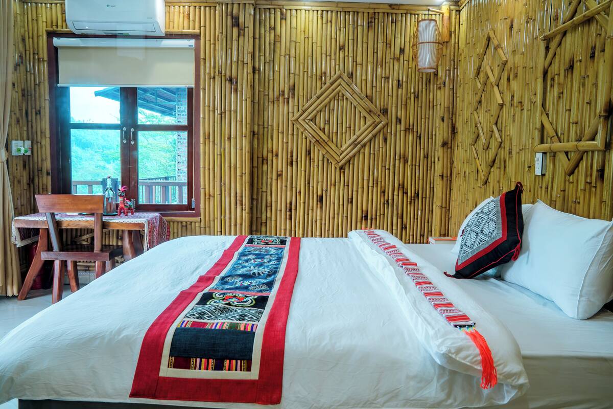 Quarto com cama, escrivaninha e janela.