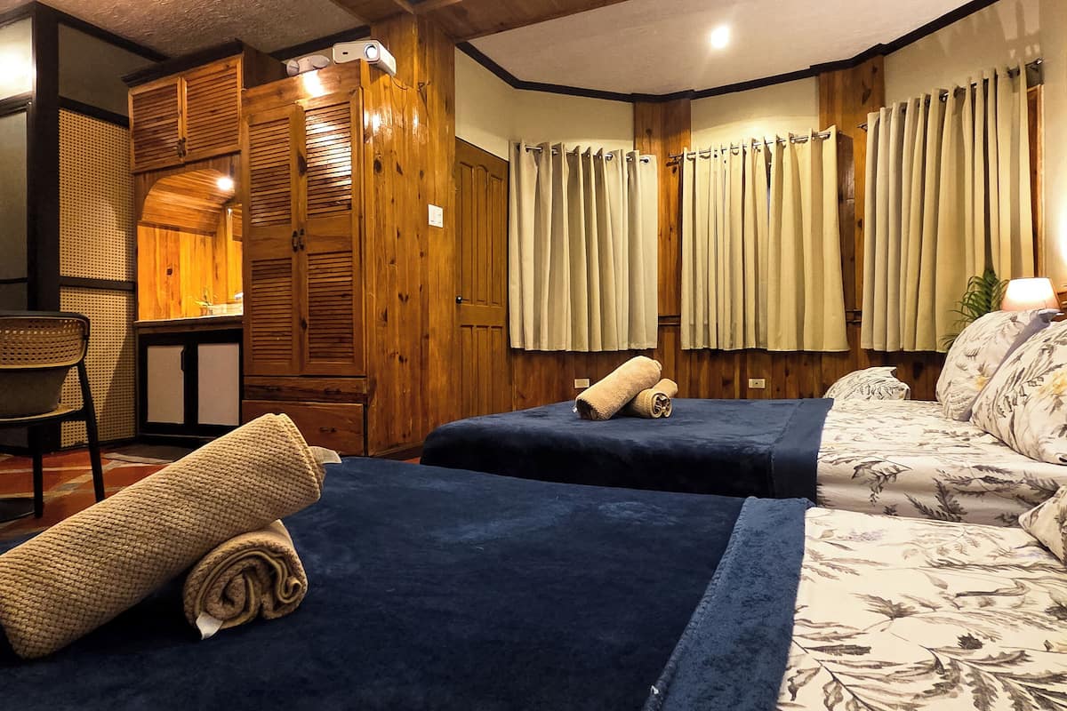 Quarto com duas camas, uma cadeira e um guarda-roupa de madeira.